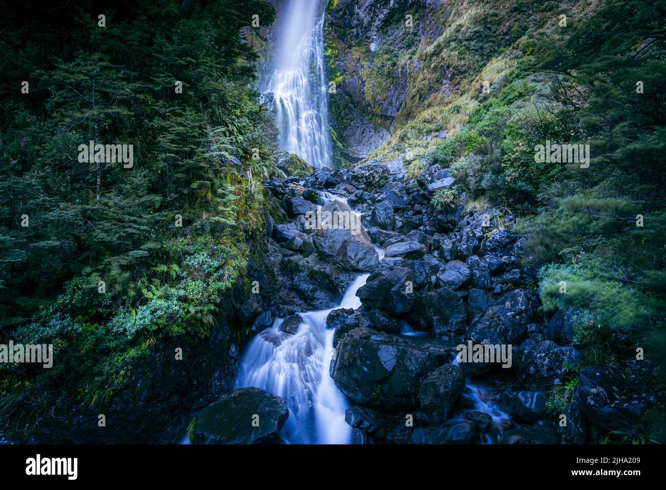 Waterfall in Southern Alps dropping down rock face and tumbling over ...