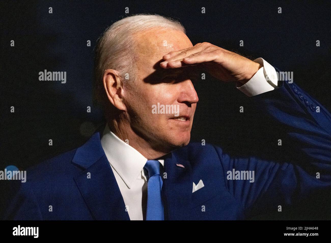 United States President Joe Biden shields his eyes from the bright ...