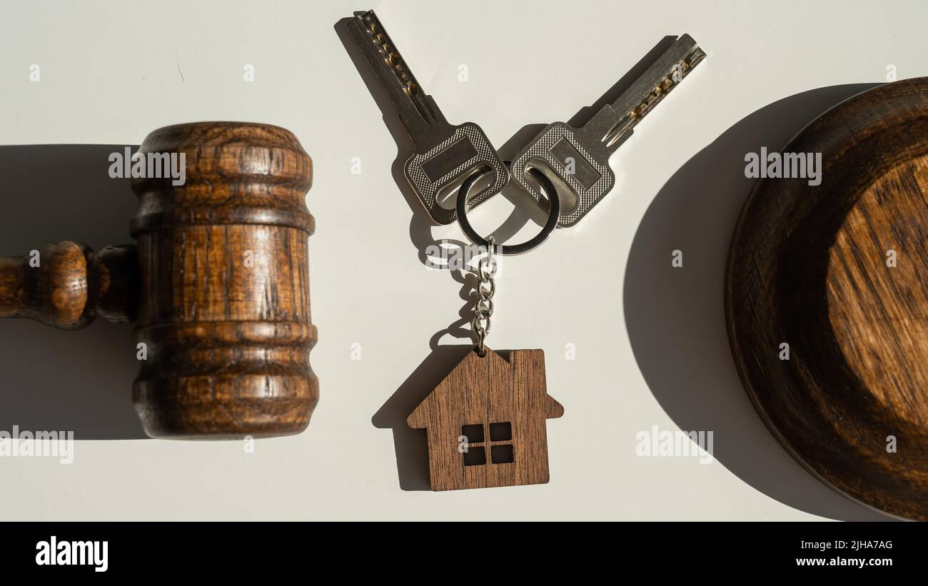 Keys with a keychain in the shape of a house and a judge's gavel on a ...