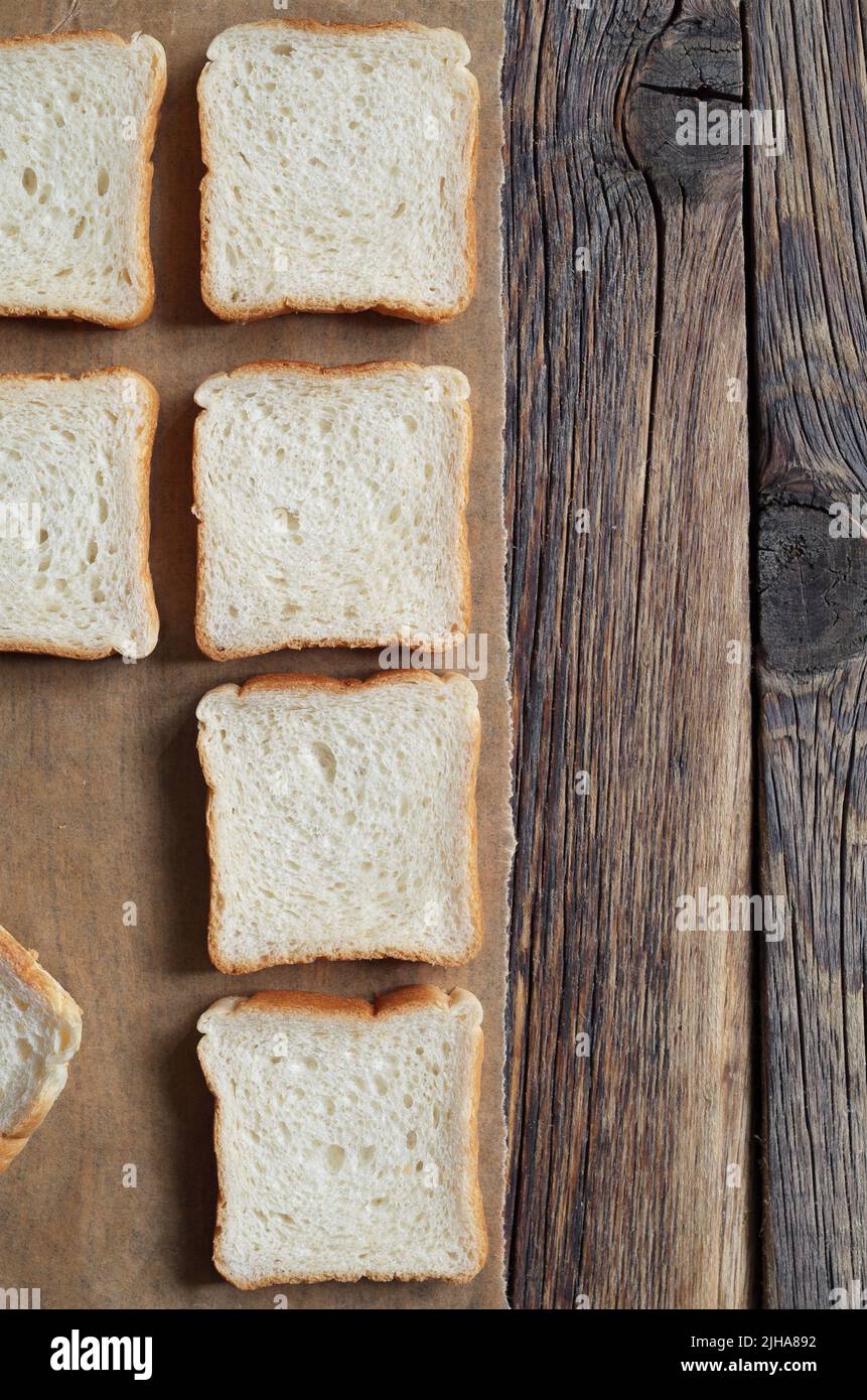 Mini toasts arranged vertically in a row on parchment paper, on an old ...