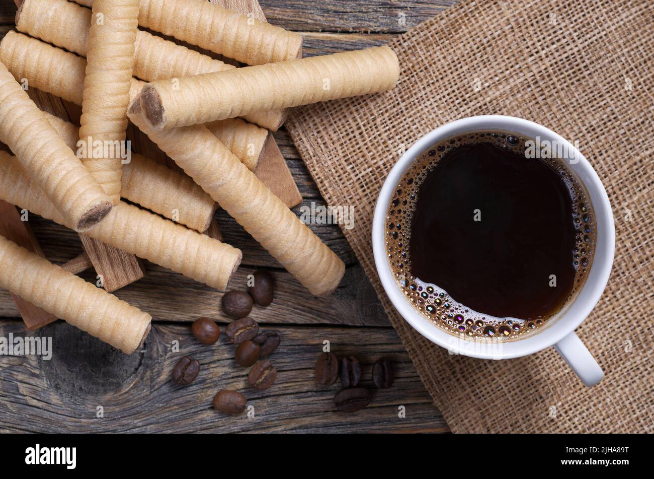 Chocolate waffle rolls and cup of coffee on rustic table, top view ...