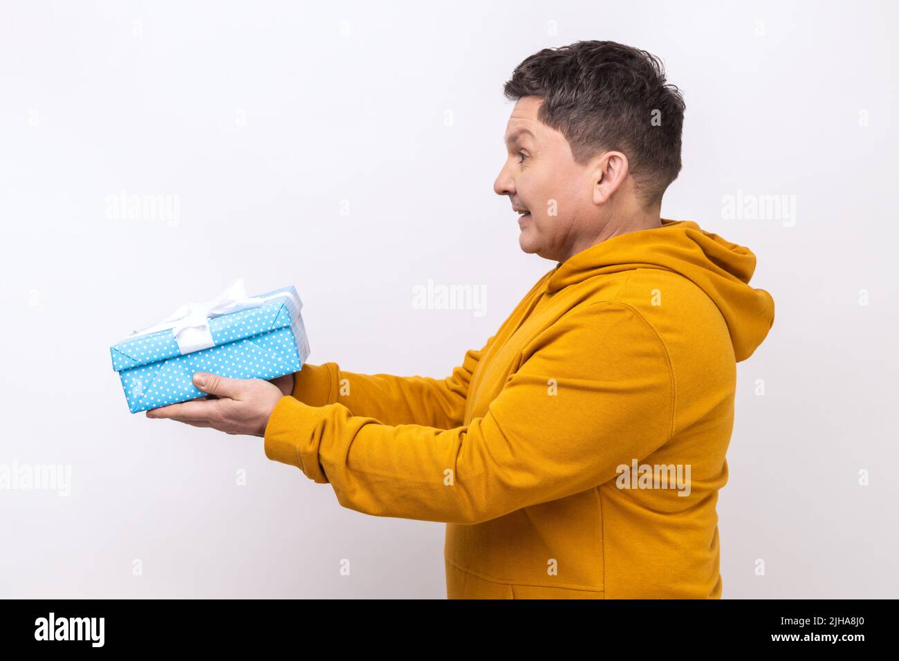 Side view portrait of positive generous man smiling and giving gift box ...