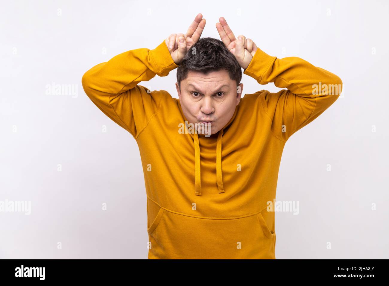 Portrait of aggressive bully man holding fingers above head showing ...