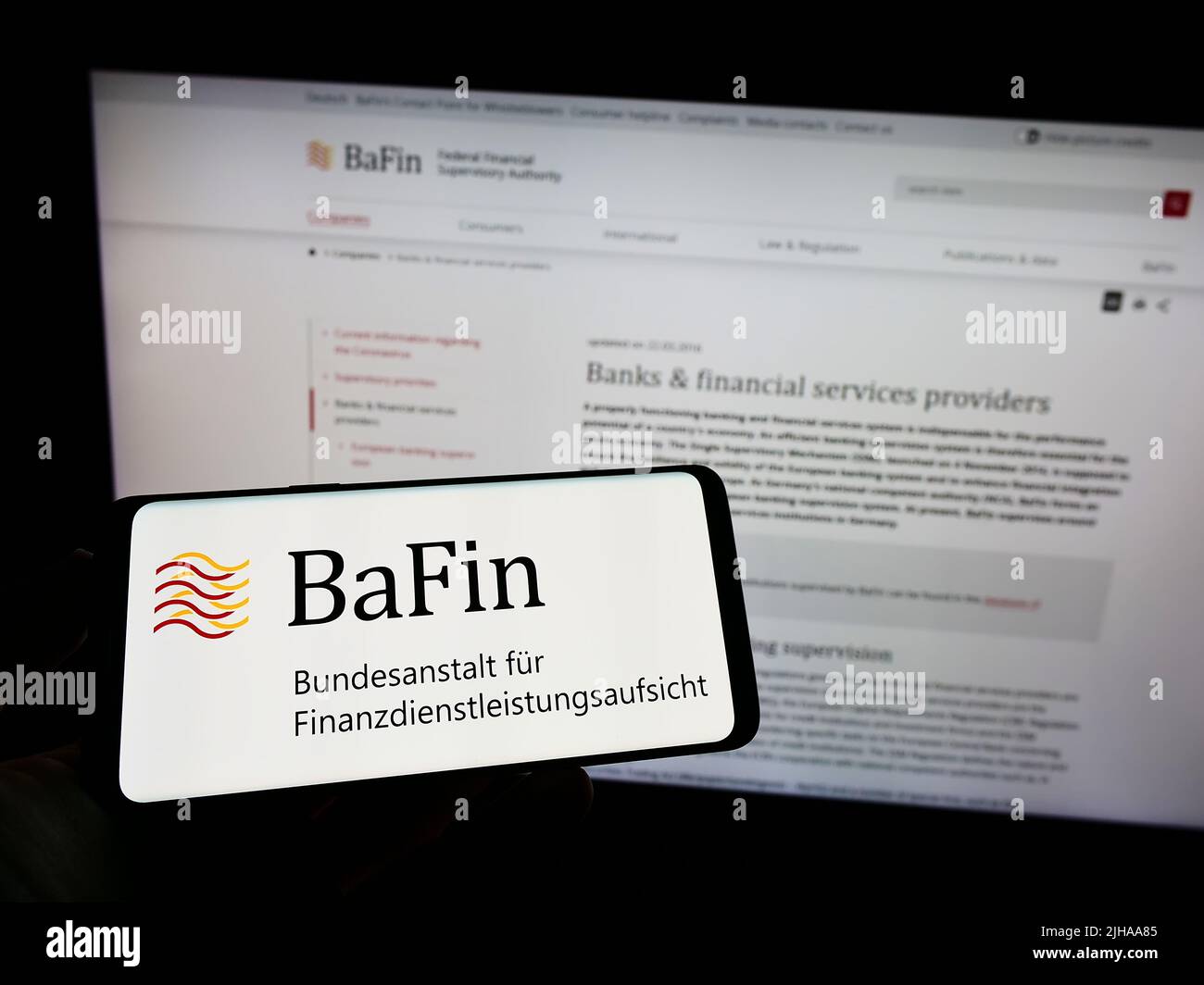 Person holding mobile phone with logo of German financial supervisory ...