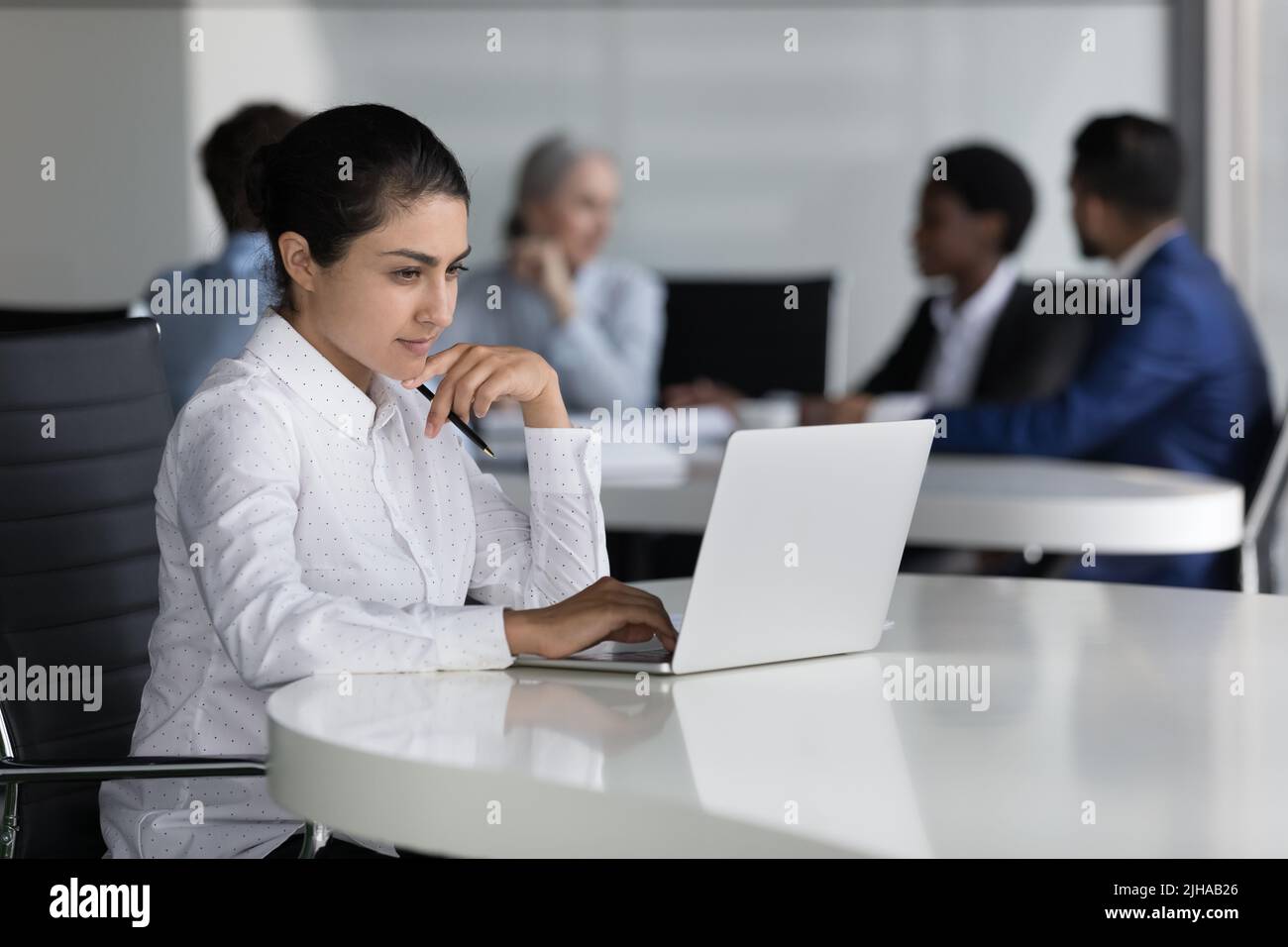 Focused busy young Indian worker using computer in co-working space ...