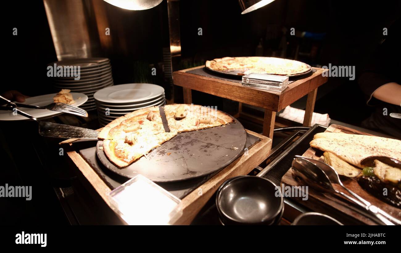 Hot Pizza Pans Under a Heat Lamp at a Buffet Stock Photo - Alamy