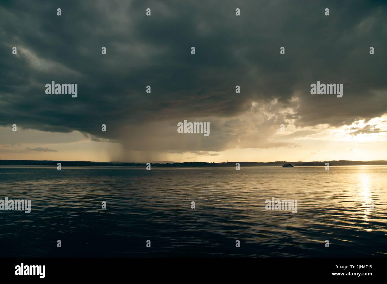 Dramatic sunset with stormy sky and rain over the Constance lake ...