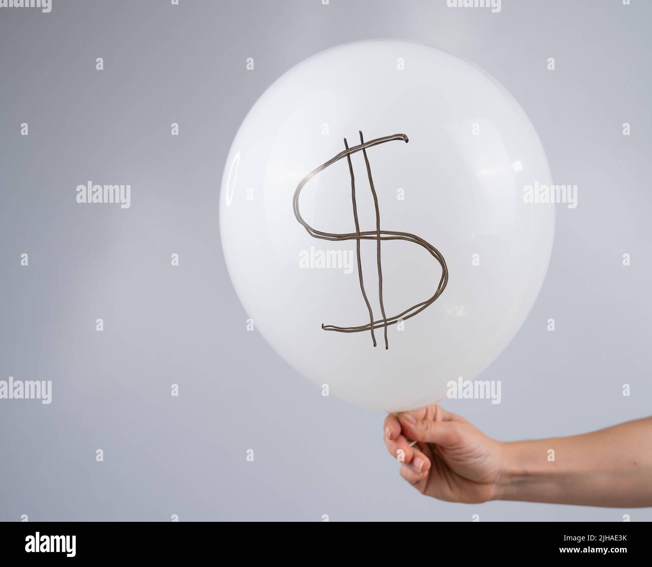 A woman is holding a balloon with a dollar sign. The concept of an ...