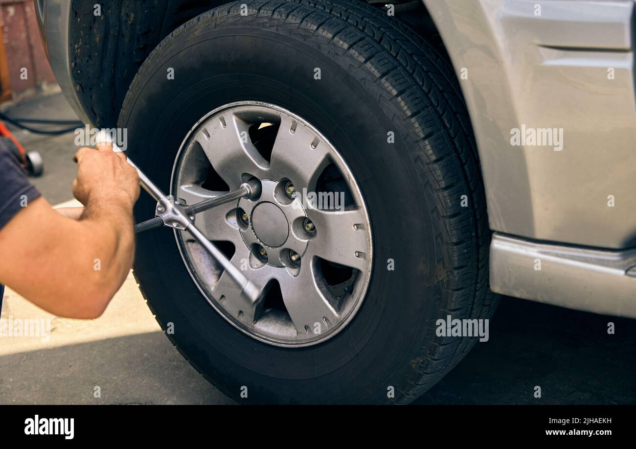 An unknown person dismantles a damaged car wheel for service Stock ...