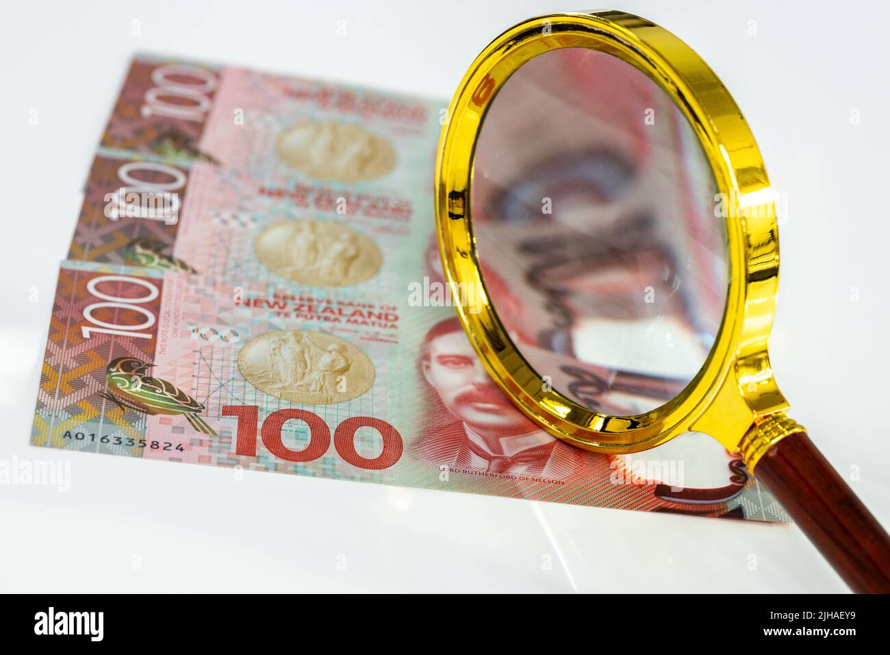 New Zealand money, flat lay, 100 dollar bills, magnifying glass, white ...