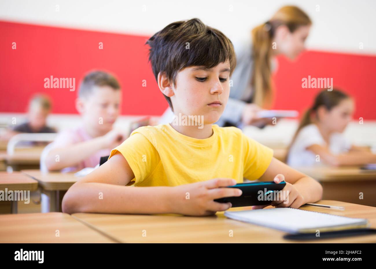 Focused tween schoolboy using mobile phone at lesson in class Stock ...