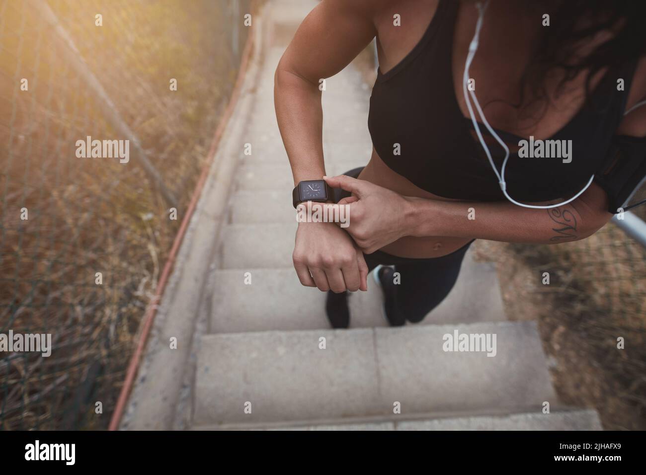 Sporty woman checking the time on a smartwatch while standing on a ...