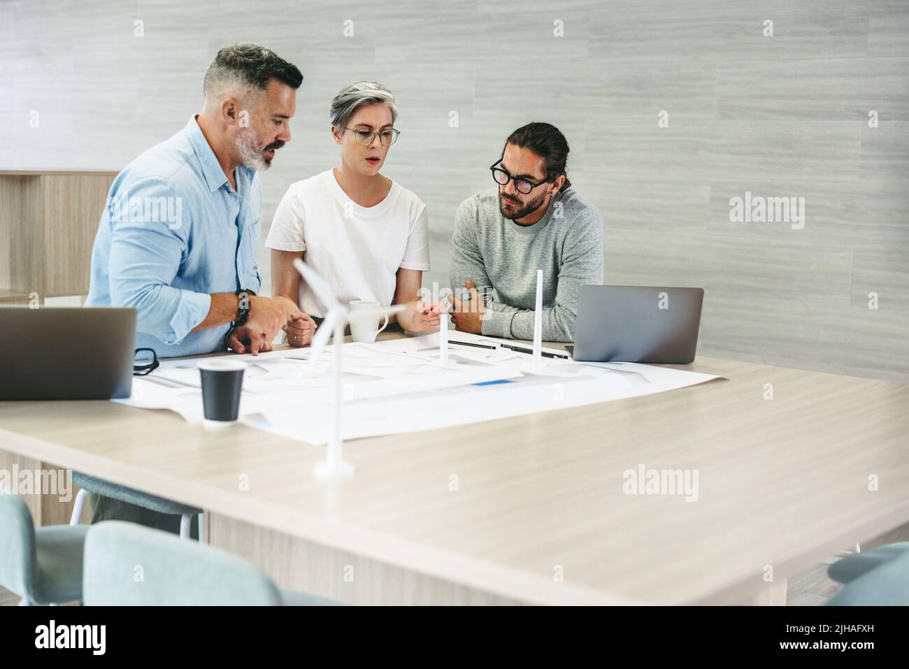 Three creative design professionals working with wind turbine ...