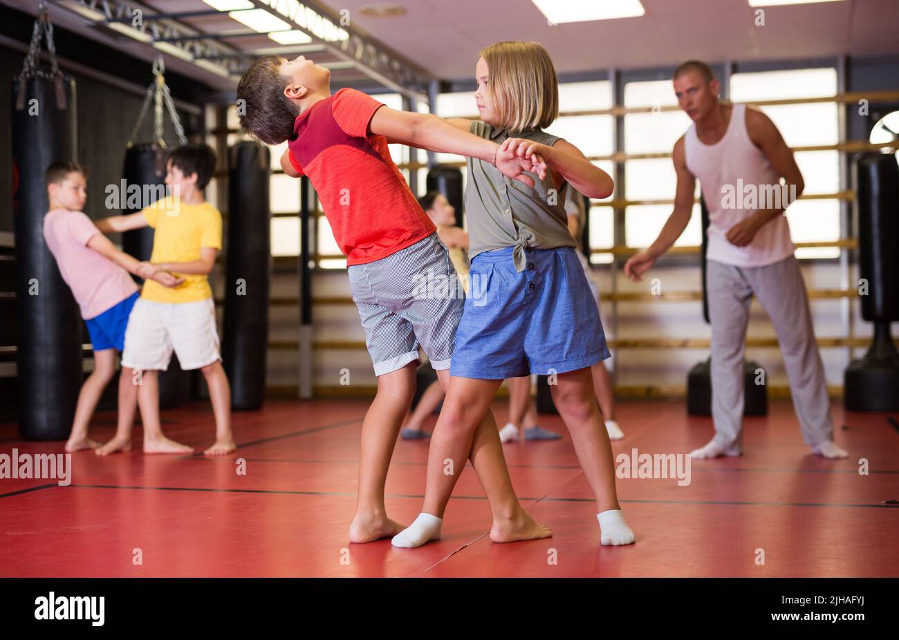 Preteen children practicing in pair self-defence movements with male ...