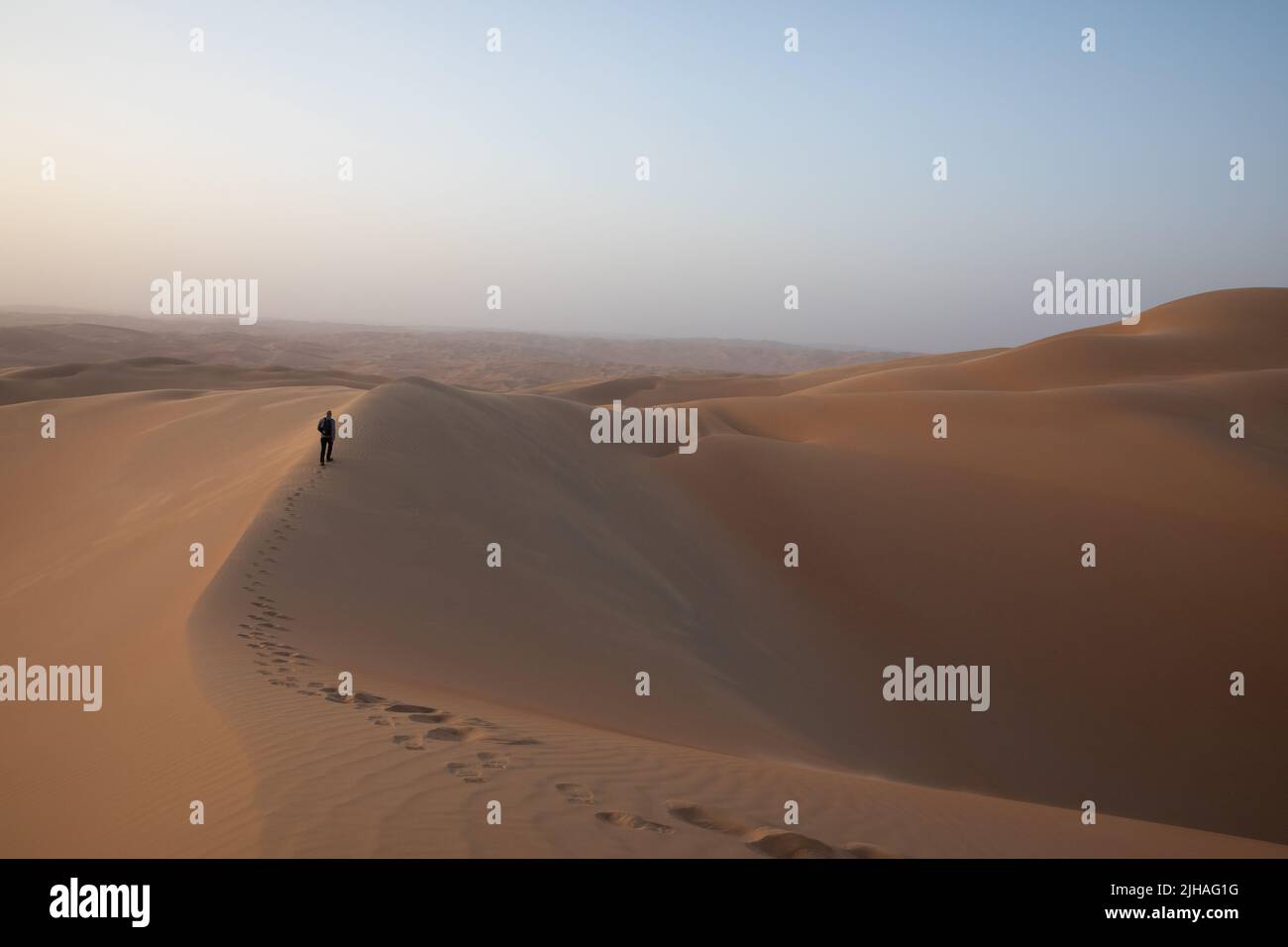 Man with a camera and backpack in the desert dunes during sunrise Stock ...