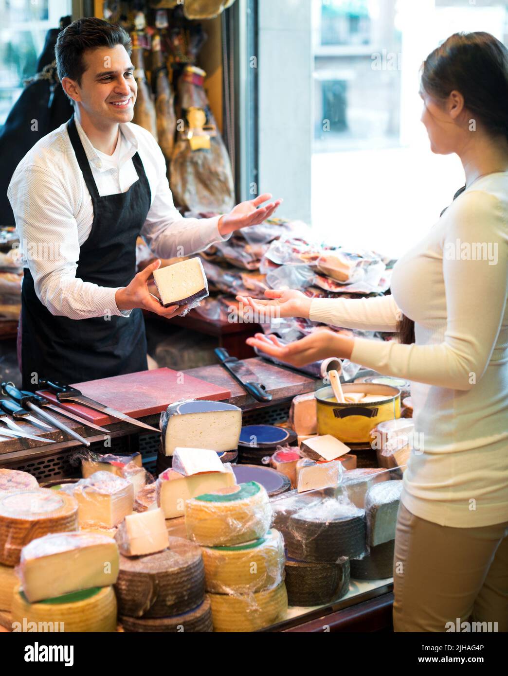 Portrait of seller offering different cheese Stock Photo - Alamy