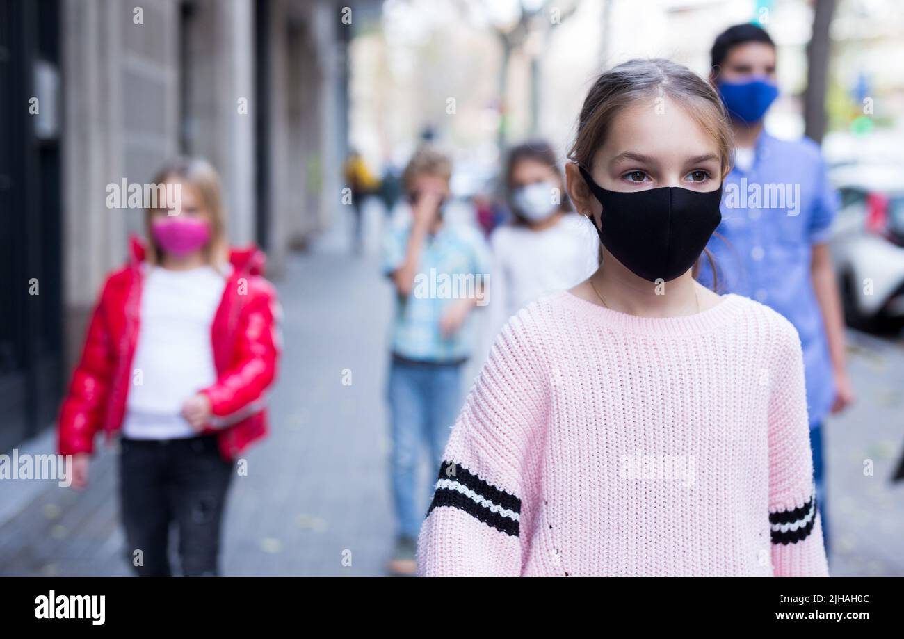 Tween girl in black mask walking along city street Stock Photo - Alamy