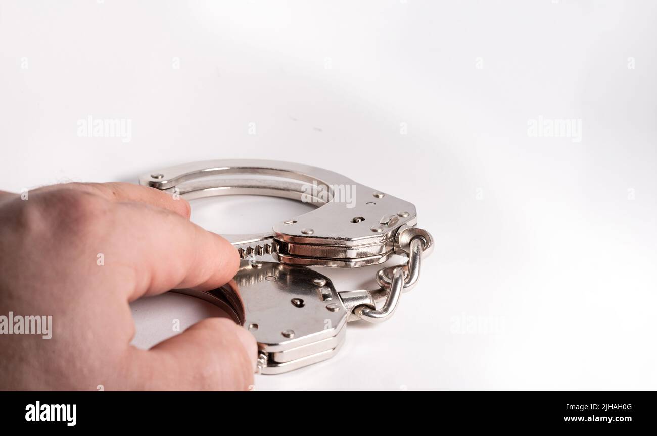 Male hand with police handcuffs, isolated on a white background. Police ...