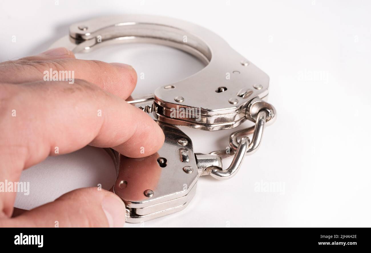 Male hand with police handcuffs, isolated on a white background. Police ...