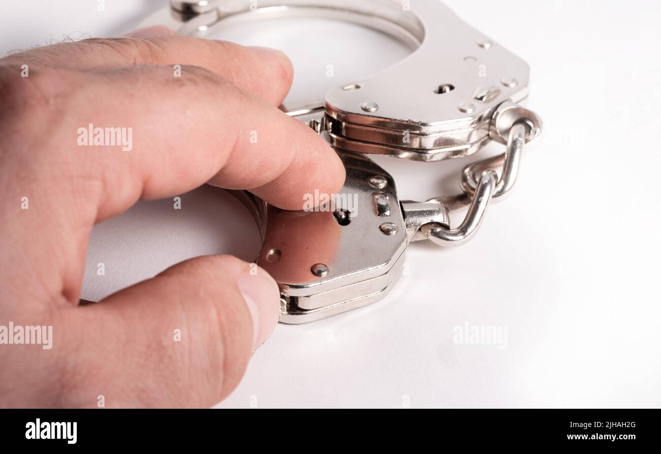 Male hand with police handcuffs, isolated on a white background. Police ...