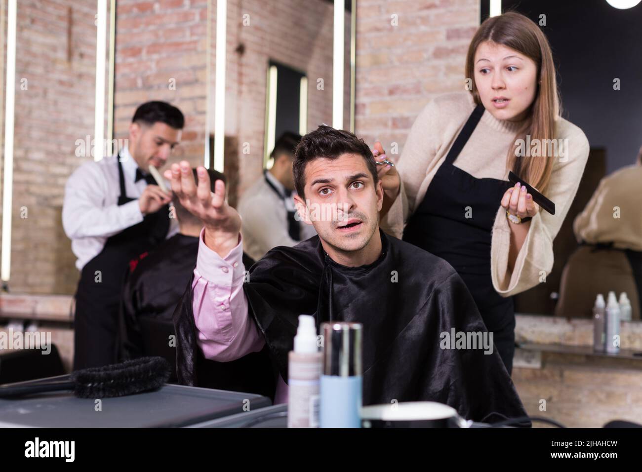 Shocked man with apologetic hairdresser at barbershop Stock Photo - Alamy