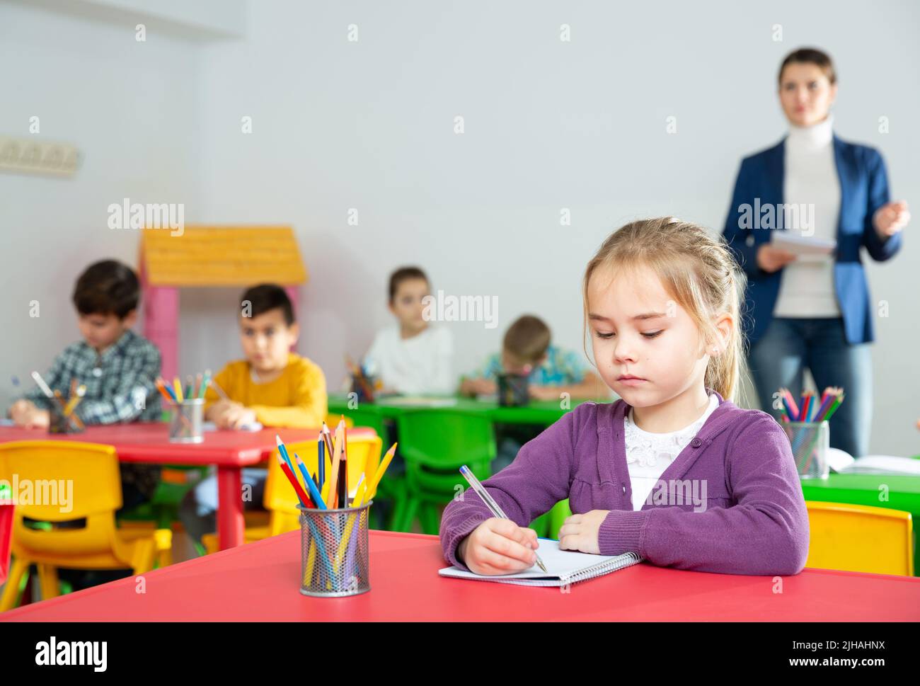 Diligent schoolgirl writing at lessons Stock Photo - Alamy