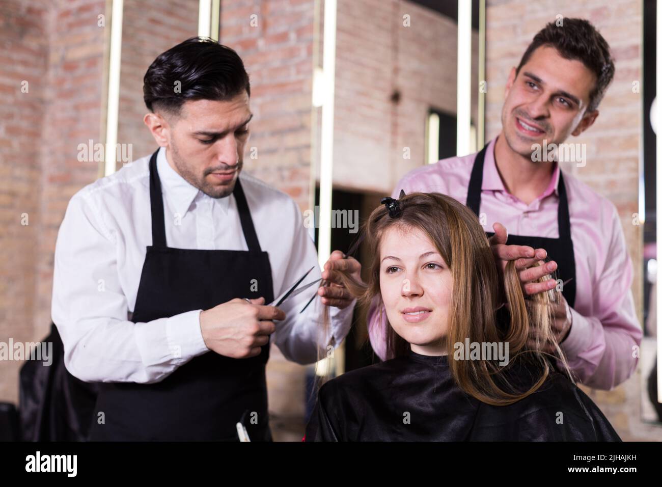 Two hairdressers making hairstyle for female client Stock Photo - Alamy