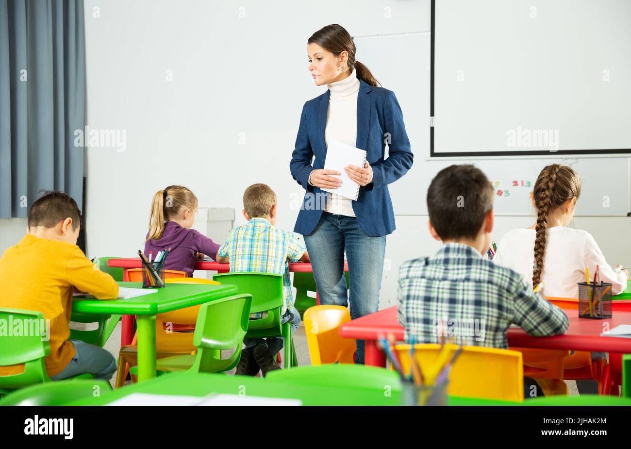 Teacher controlling writing of elementary school students Stock Photo ...