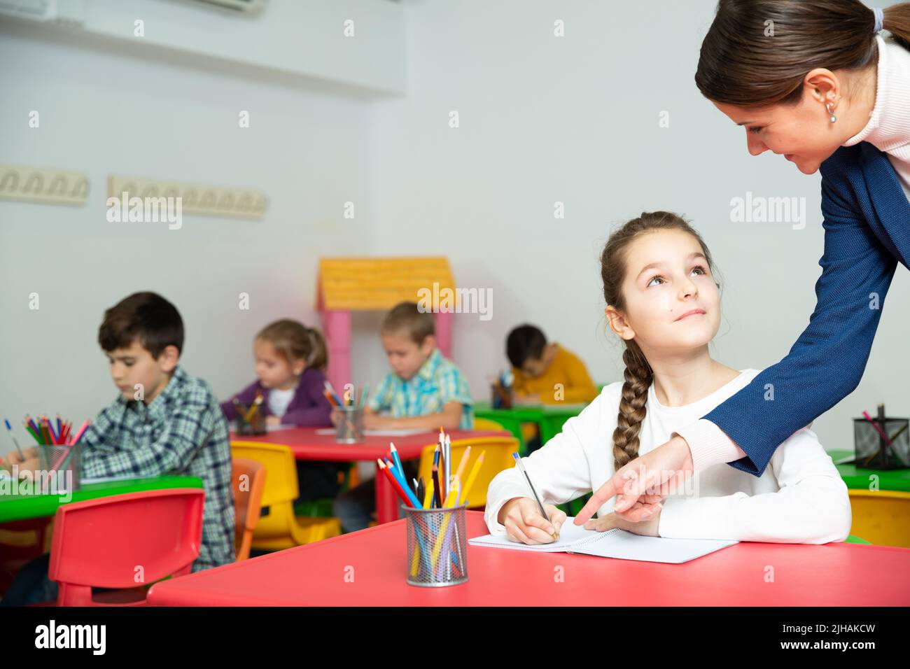 Female teacher helps schoolgirl complete an assignment in an elementary ...