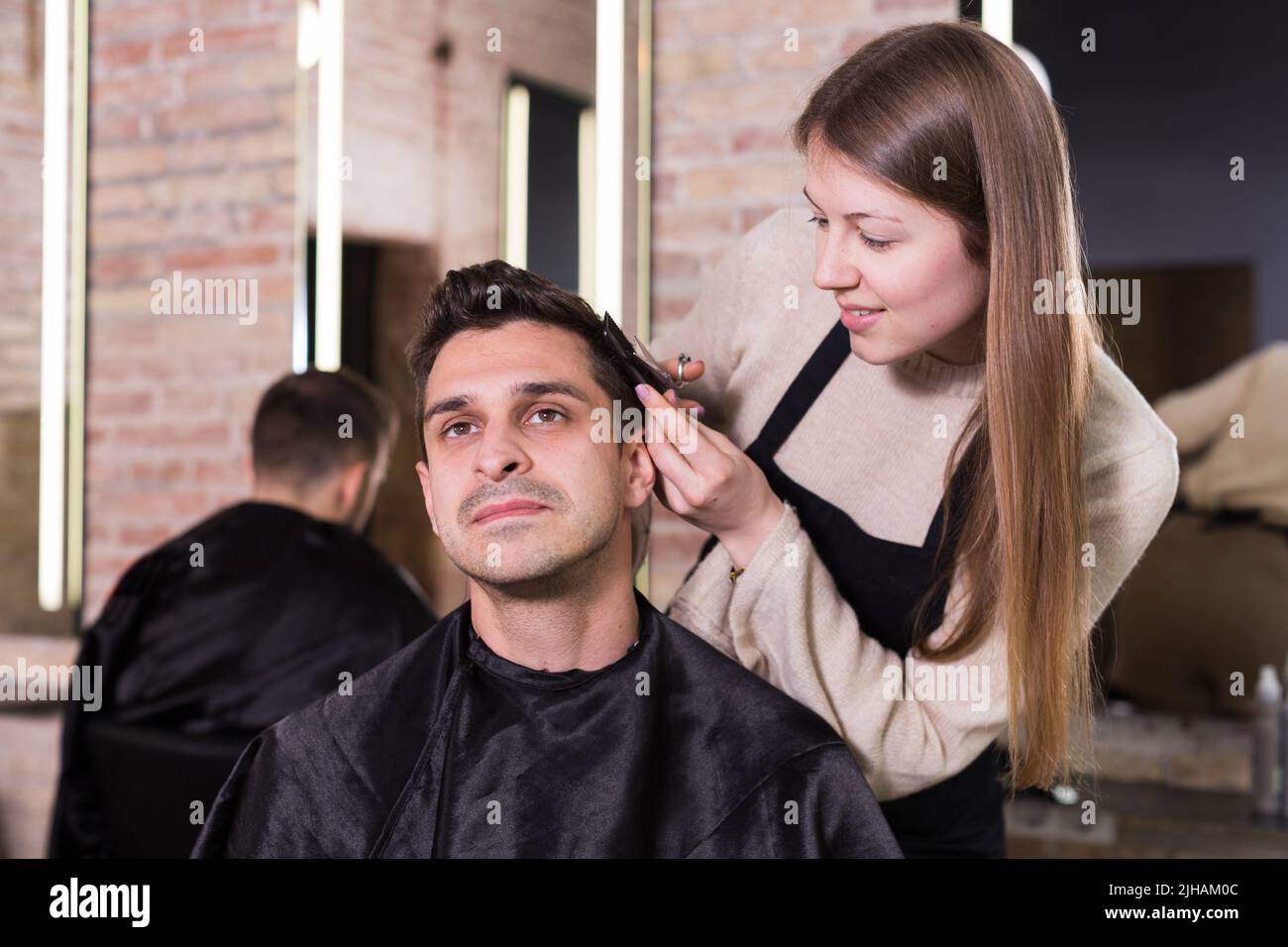 Woman barber making hairstyle for male client Stock Photo - Alamy
