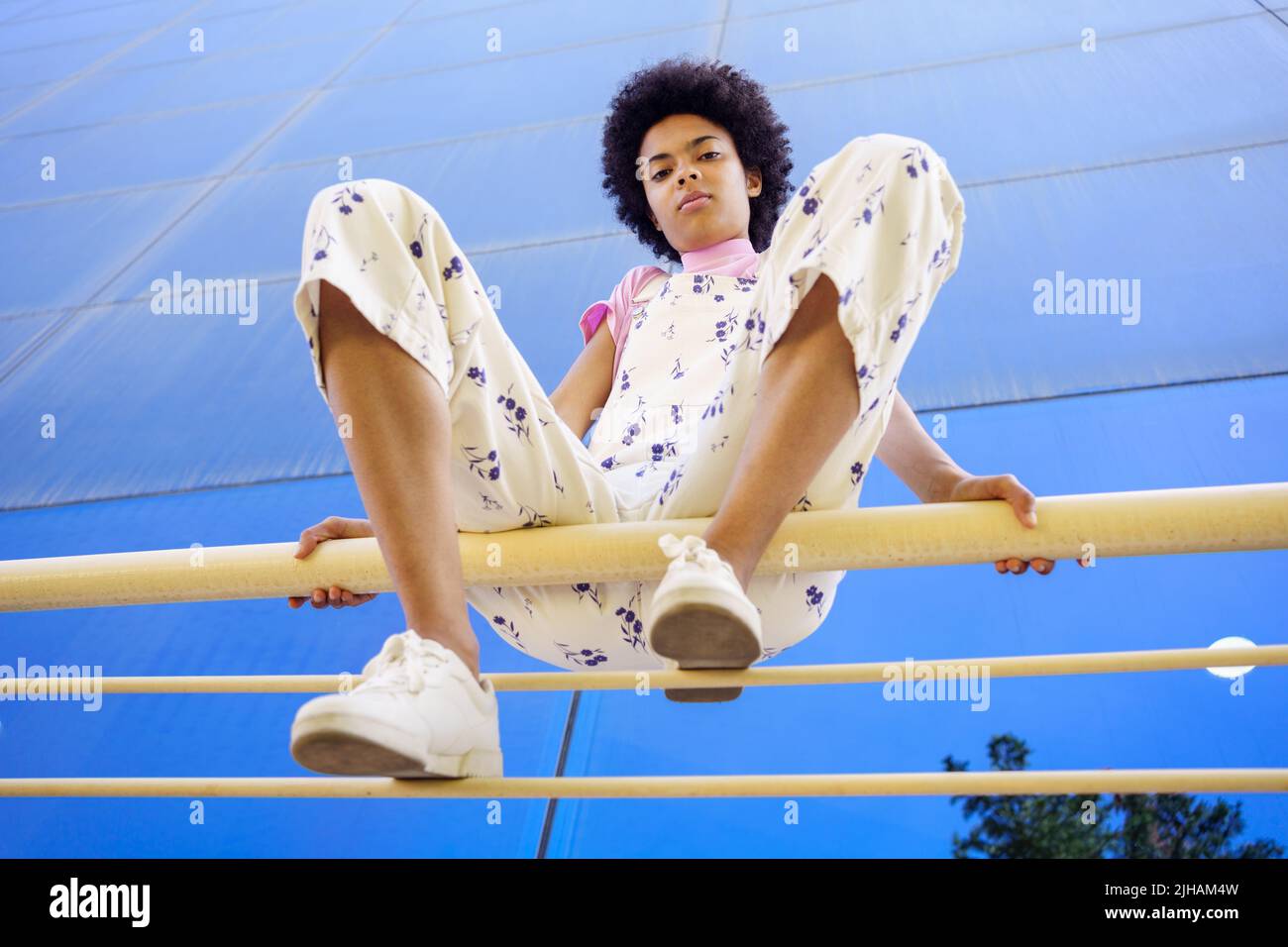 Black woman sitting on railing in city Stock Photo - Alamy