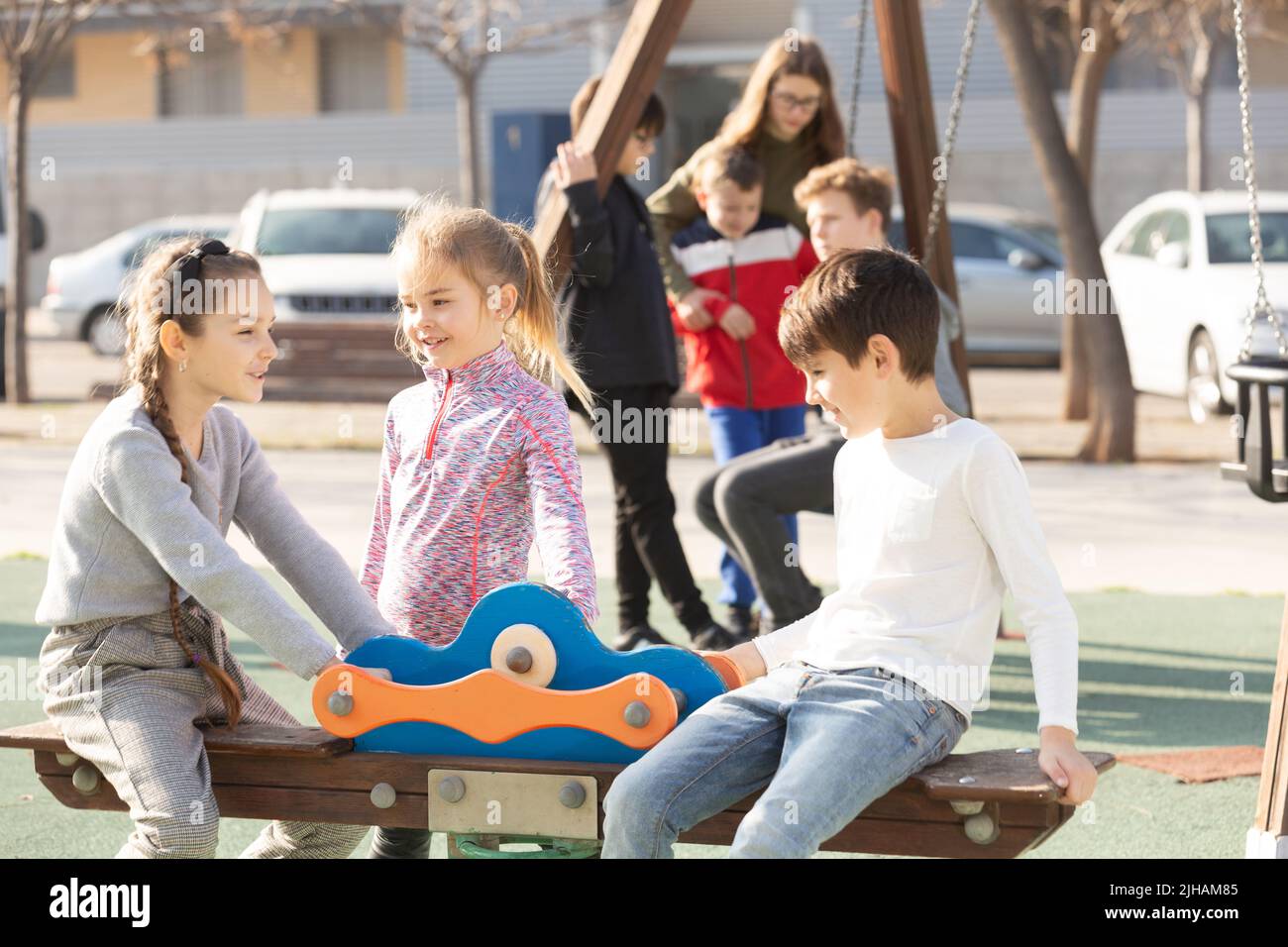 Company of kids are teetering on the swing on the playground Stock ...