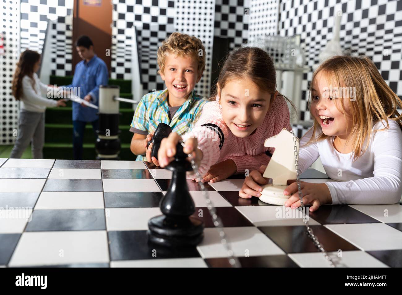 Tweenagers solving conundrum in lost room designed as chessboard Stock ...