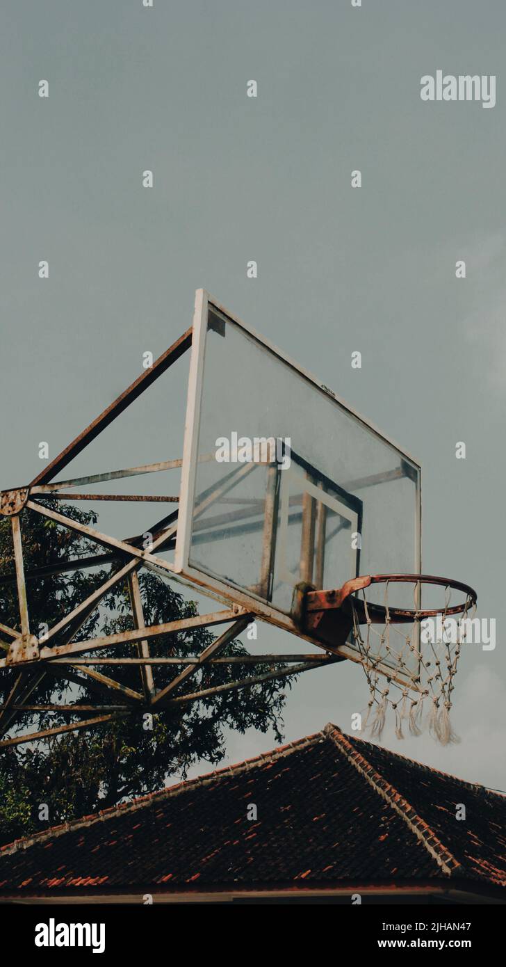 A vertical shot of an old rusty basketball hoop in a house garden Stock ...