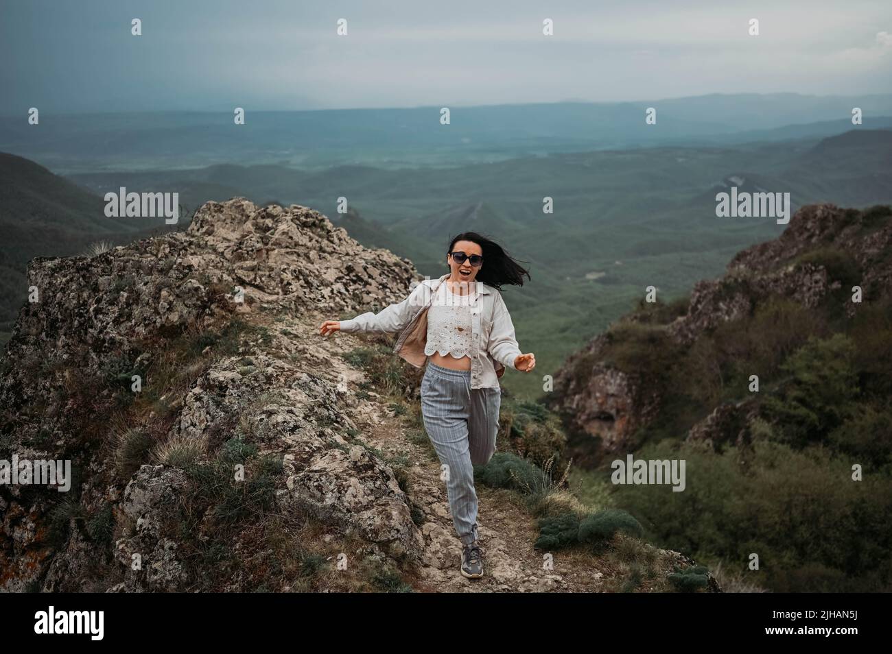 Woman happy tourist hiking up runs from top of mountain enjoying nature ...