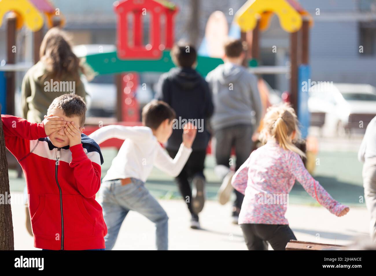 Boy playing hide and seek with friends Stock Photo - Alamy
