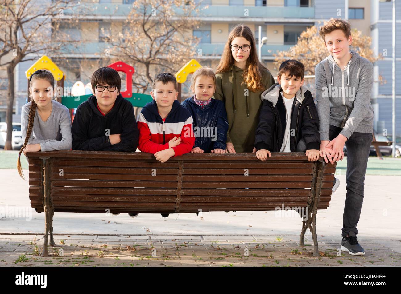 Portrait of happy kids sitting together on bench on playground Stock ...