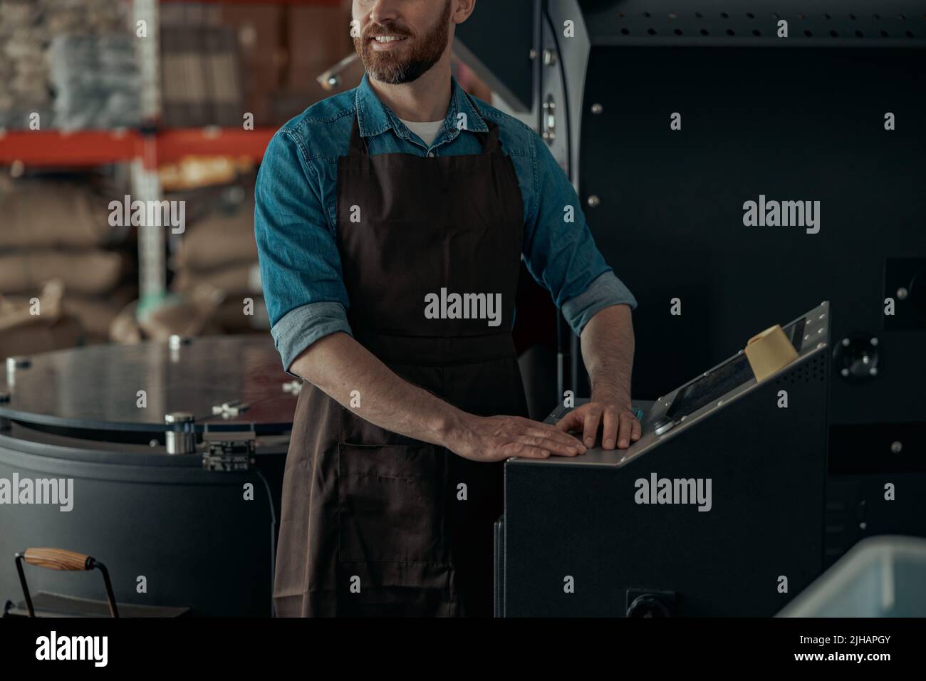 Close up of worker operating of coffee roasting machine on small ...