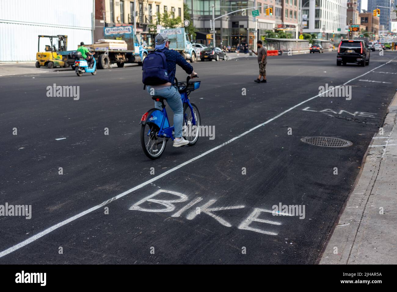 A bicyclist driving on a street out of a to be paved bike lane. New ...
