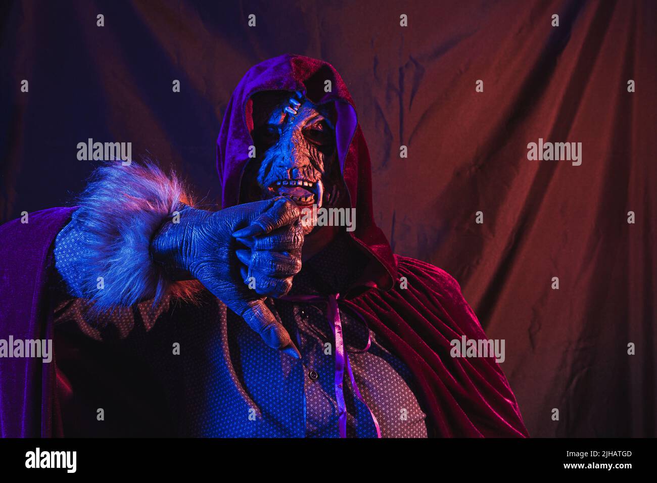 Portrait of a zombie dressed in a shirt and hooded cape making the ...