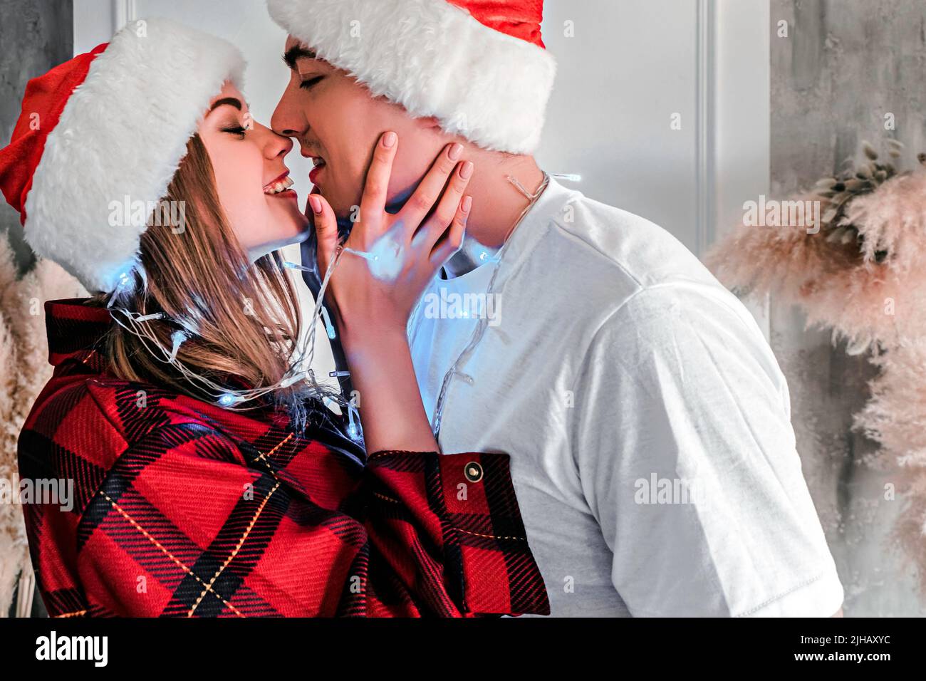 Christmas Smiling Man And Woman Wearing Santa Hats Rub Their Noses