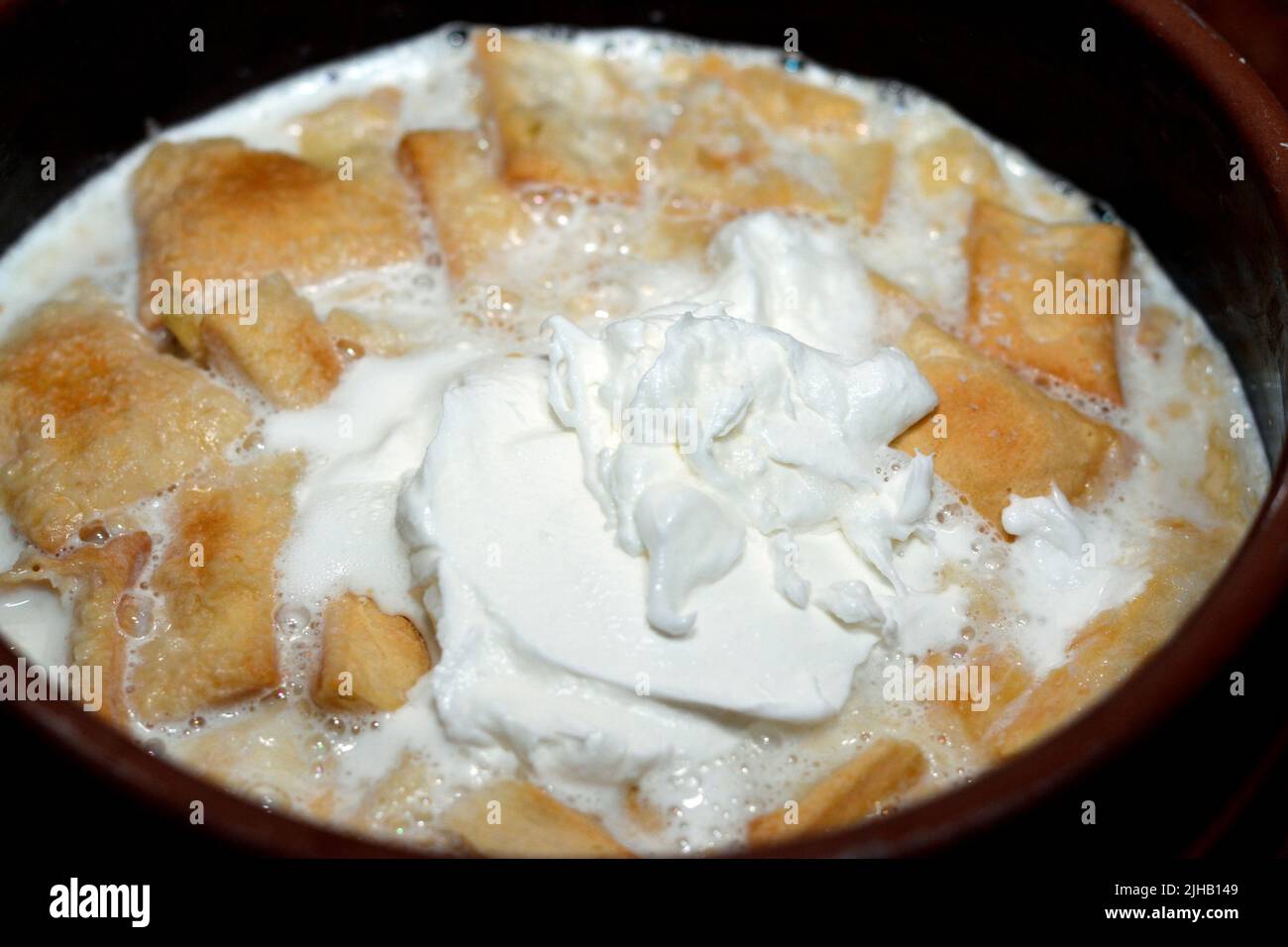 whipped cream on top of Egyptian bread pudding, milk in a brown bowl ...