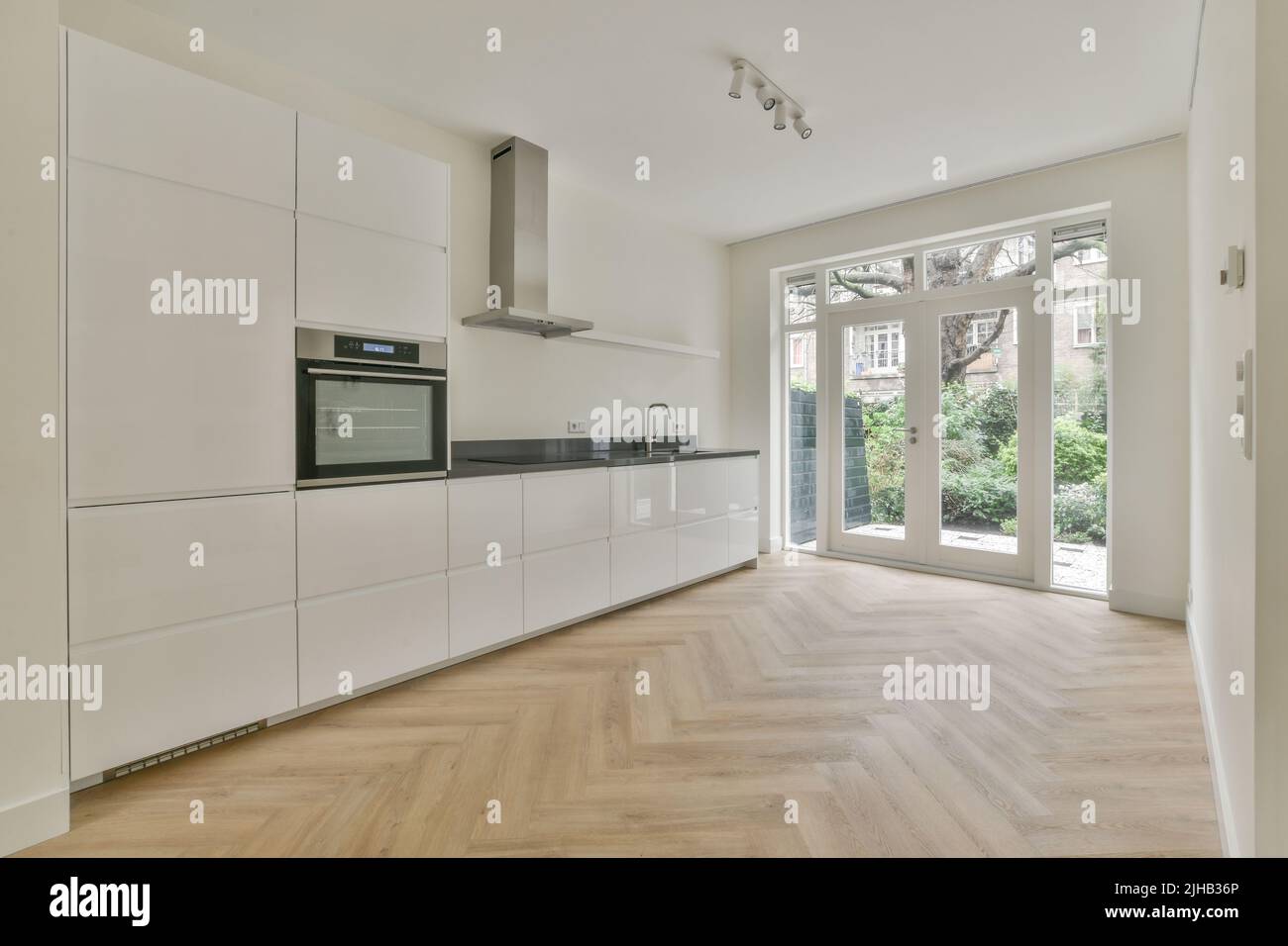 Interior of empty white kitchen with windows and wooden parquet floor ...