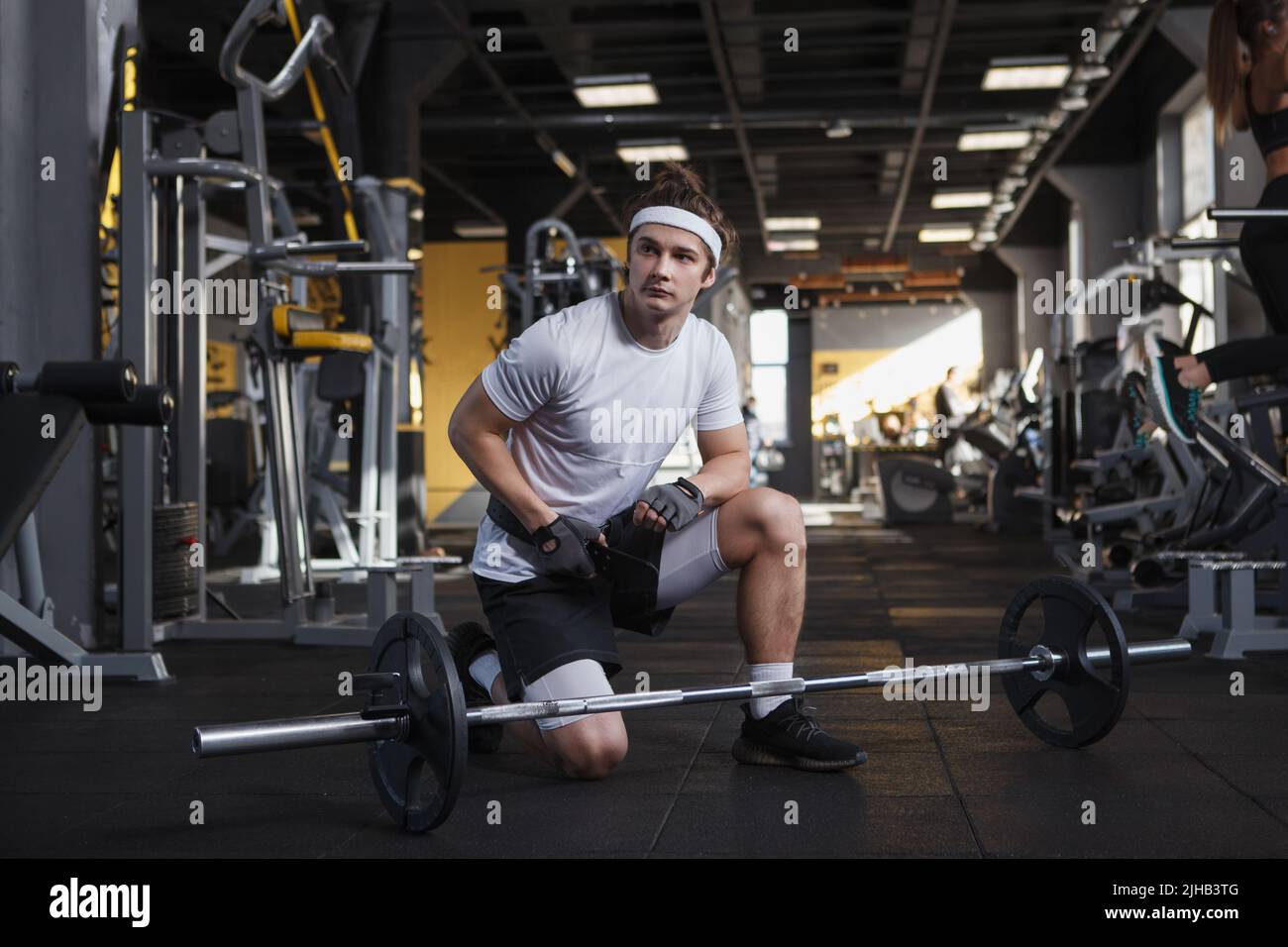 Attractive male weightlifter putting on workout belt before barbell ...