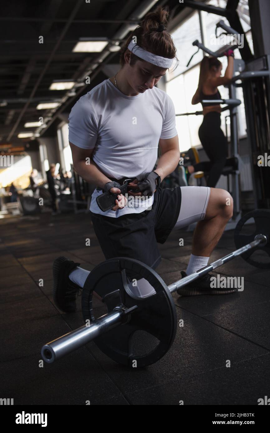 Vertical shot of a male bodybuilder putting on weighlifting belt ...