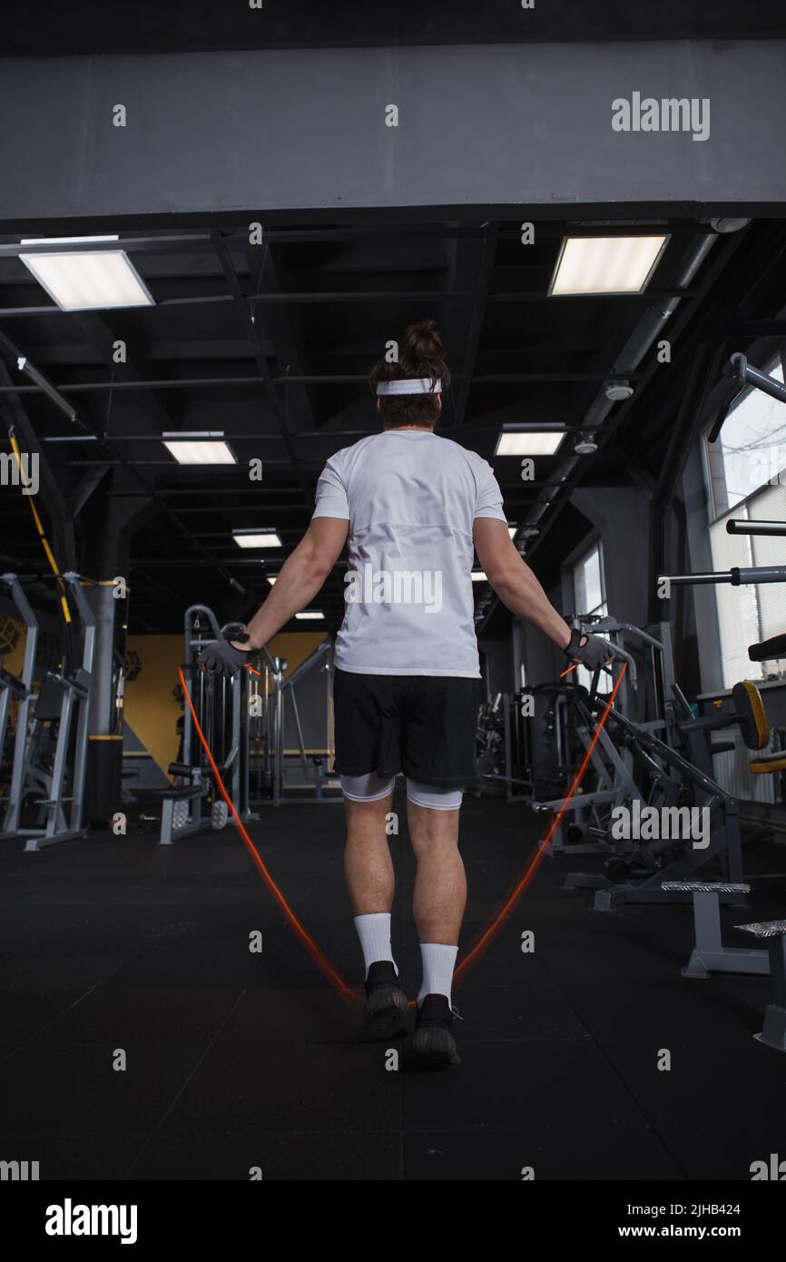 Vertical rear view shot of a male athlete exercising, jumping with ...