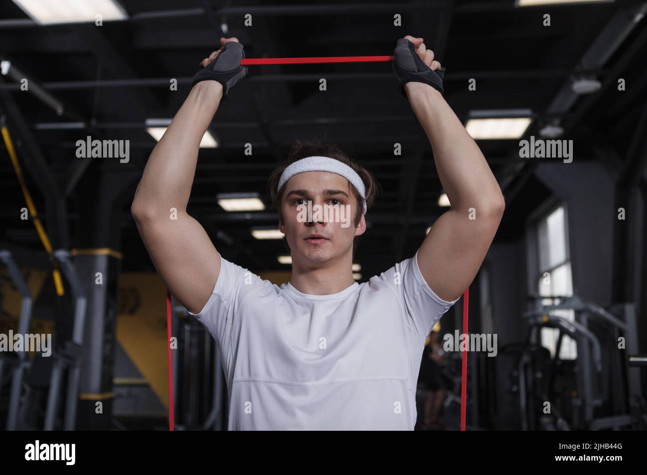 Handsome sportsman wearing headband, exercising with resistance band at ...