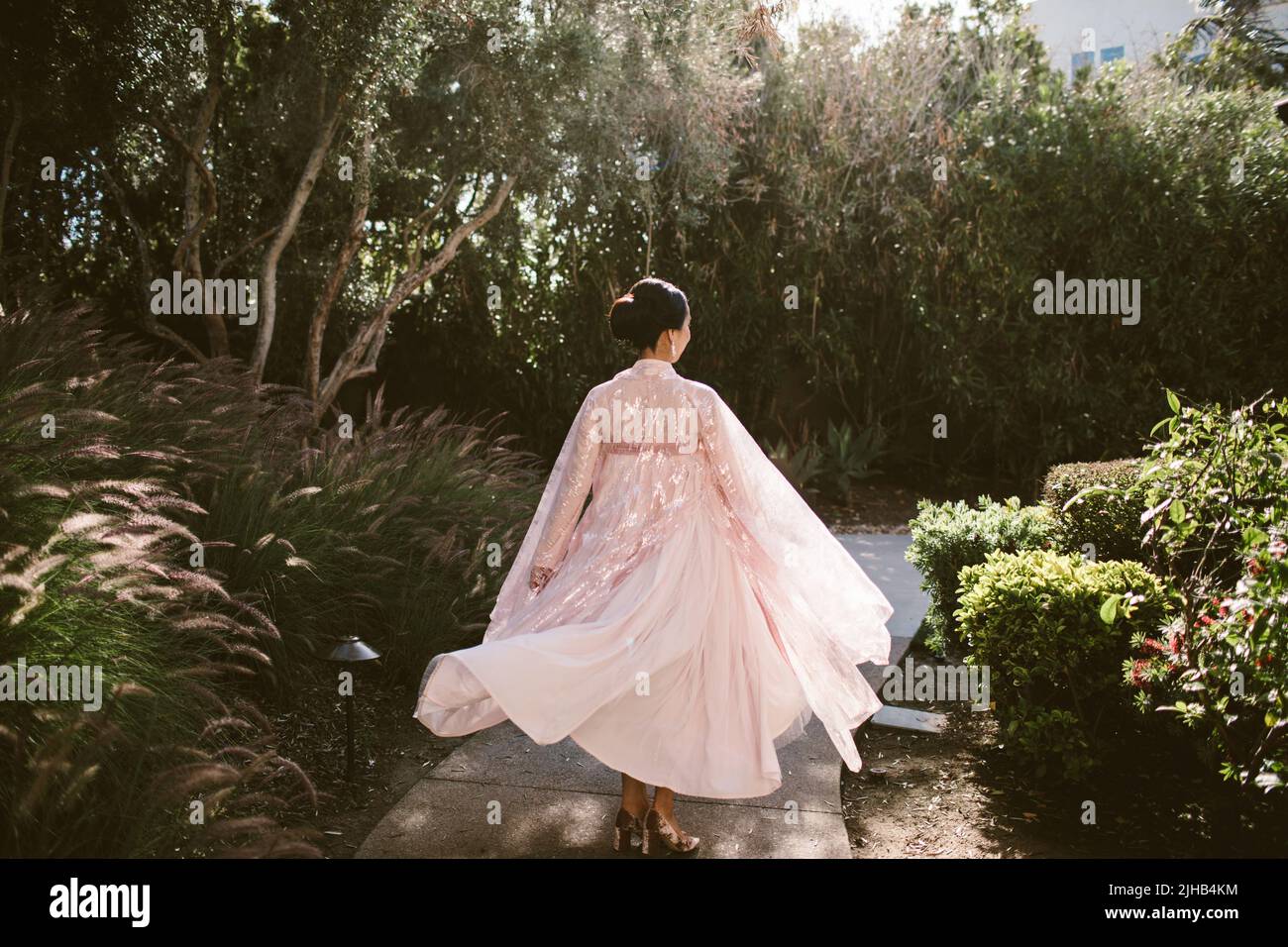 A back view of a young woman twirling in a traditional Chinese wedding ...