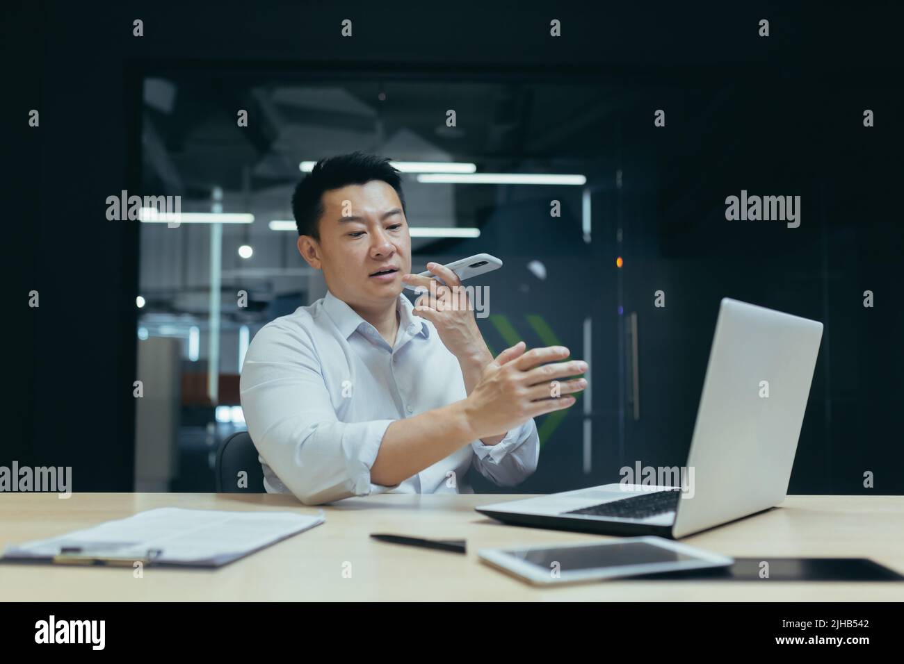 Online store. A young Asian salesman talks on the phone with customers ...