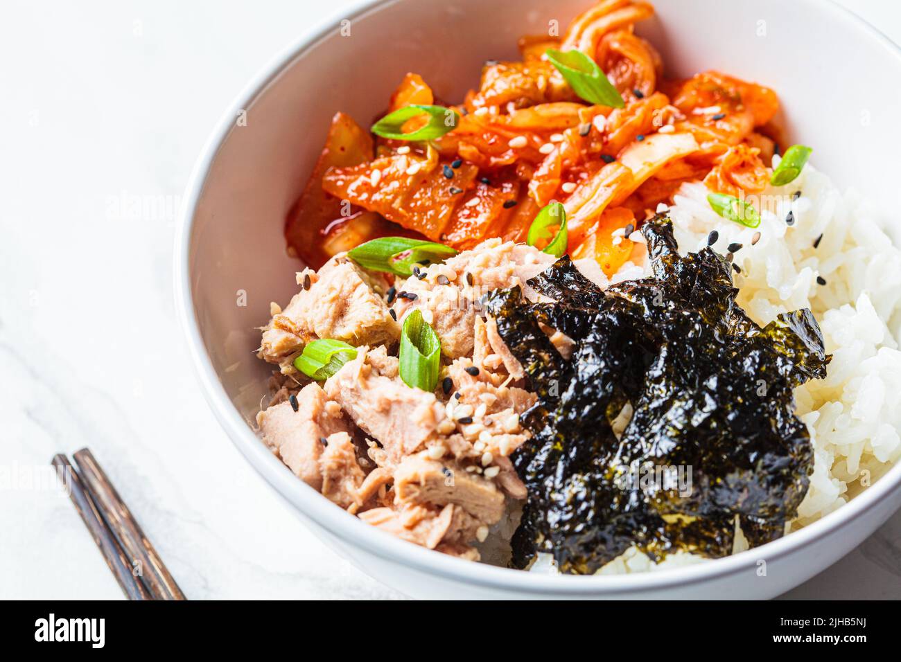 Kimchi tuna rice salad in a white bowl, closeup. Traditional Korean ...